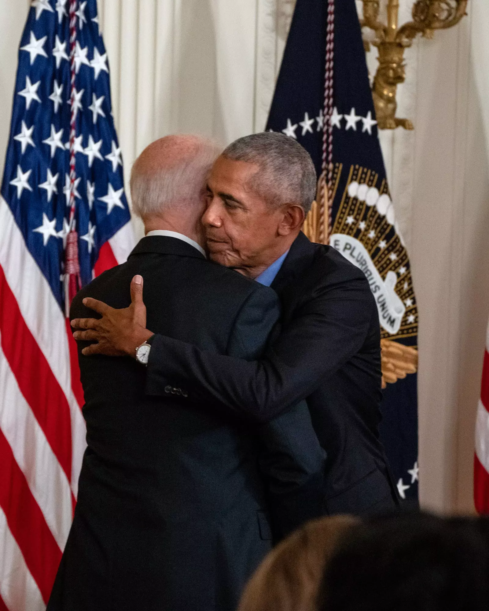 Voormalig president Barack Obama omhelst president Joe Biden terwijl vice-president Kamala Harris toekijkt nadat Obama...